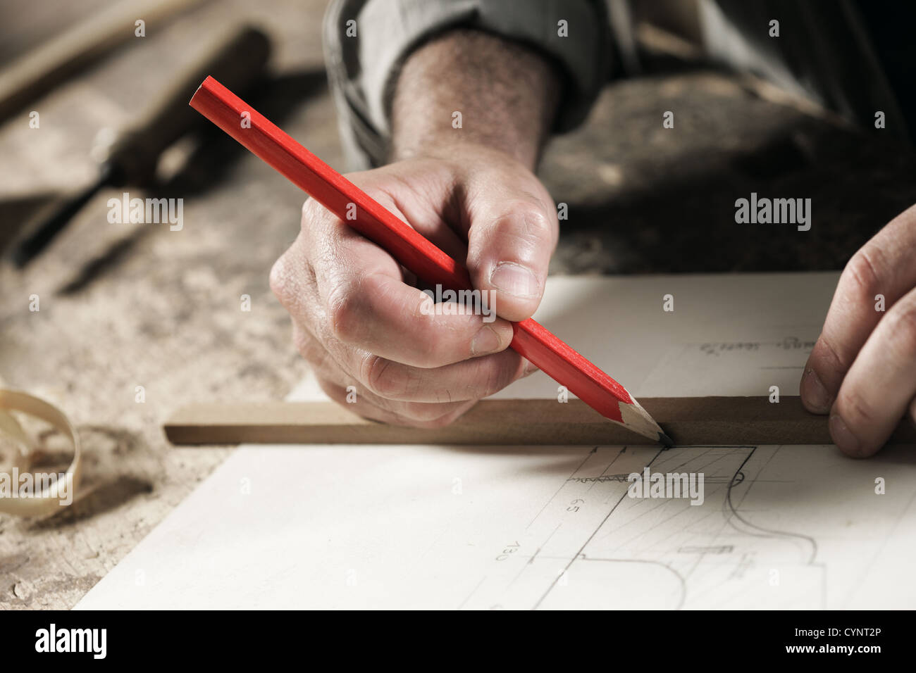 Closeup view of a carpenter using a red pencil to draw a line on a ...
