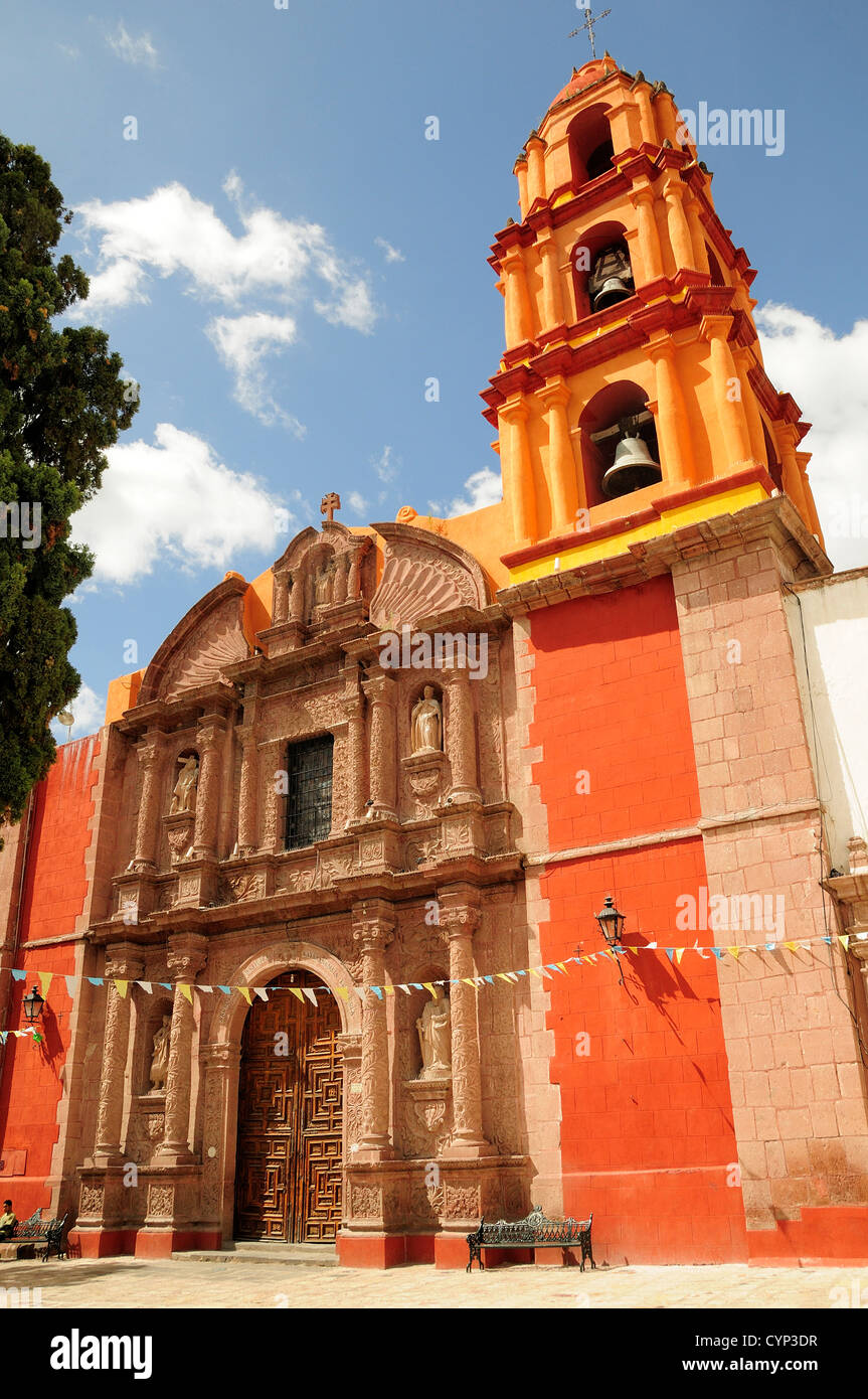 Exterior facade and bell tower of orange and yellow painted church ...