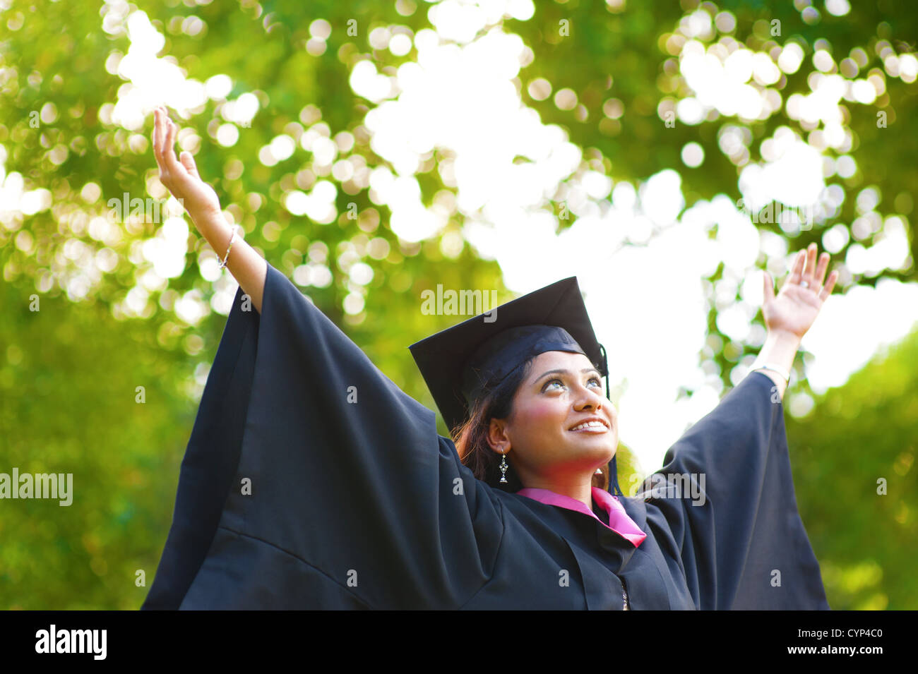 Young Asian Indian female student open arms outdoor on graduation day ...