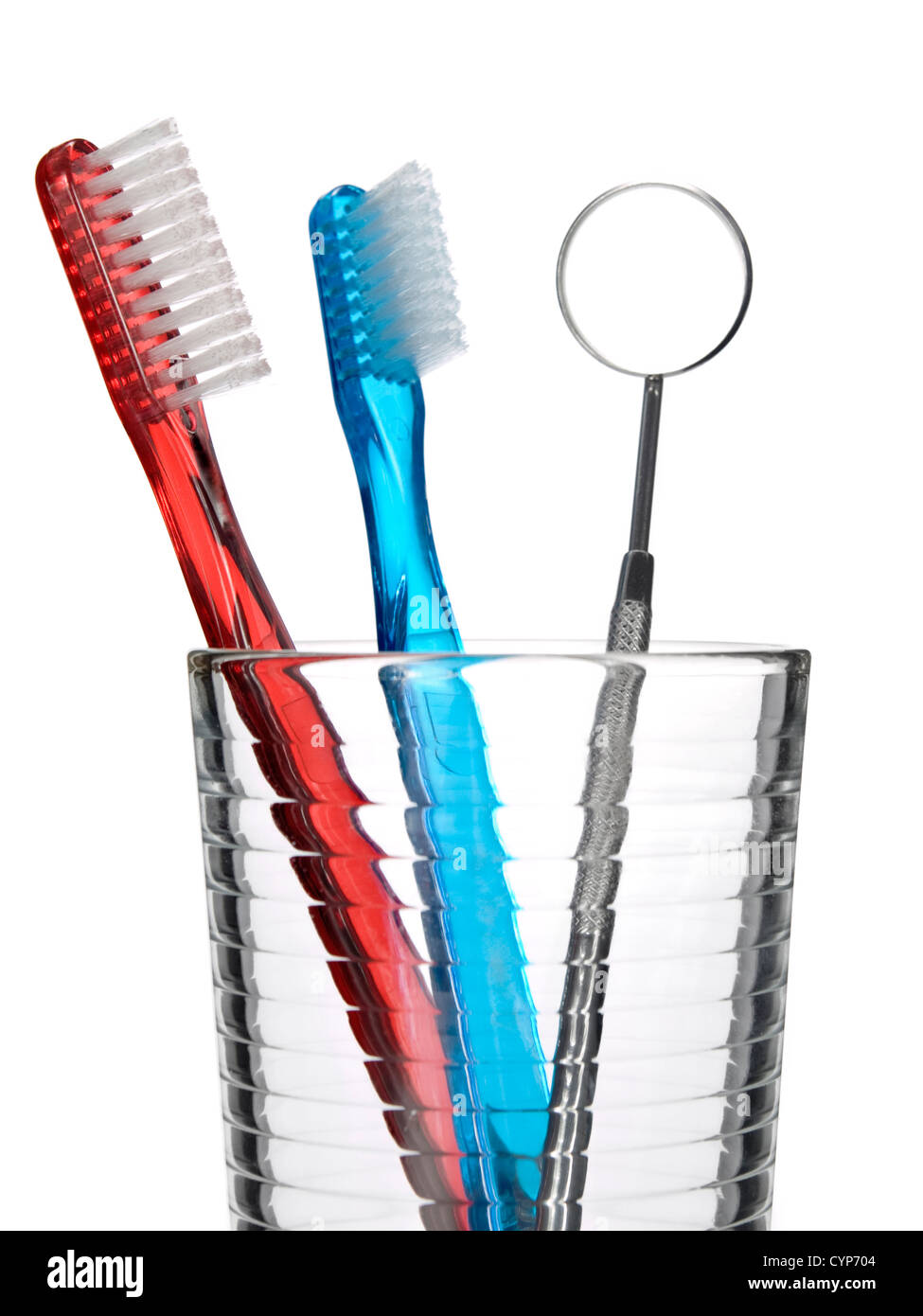 Two toothbrushes and a mouth mirror in a glass Stock Photo - Alamy
