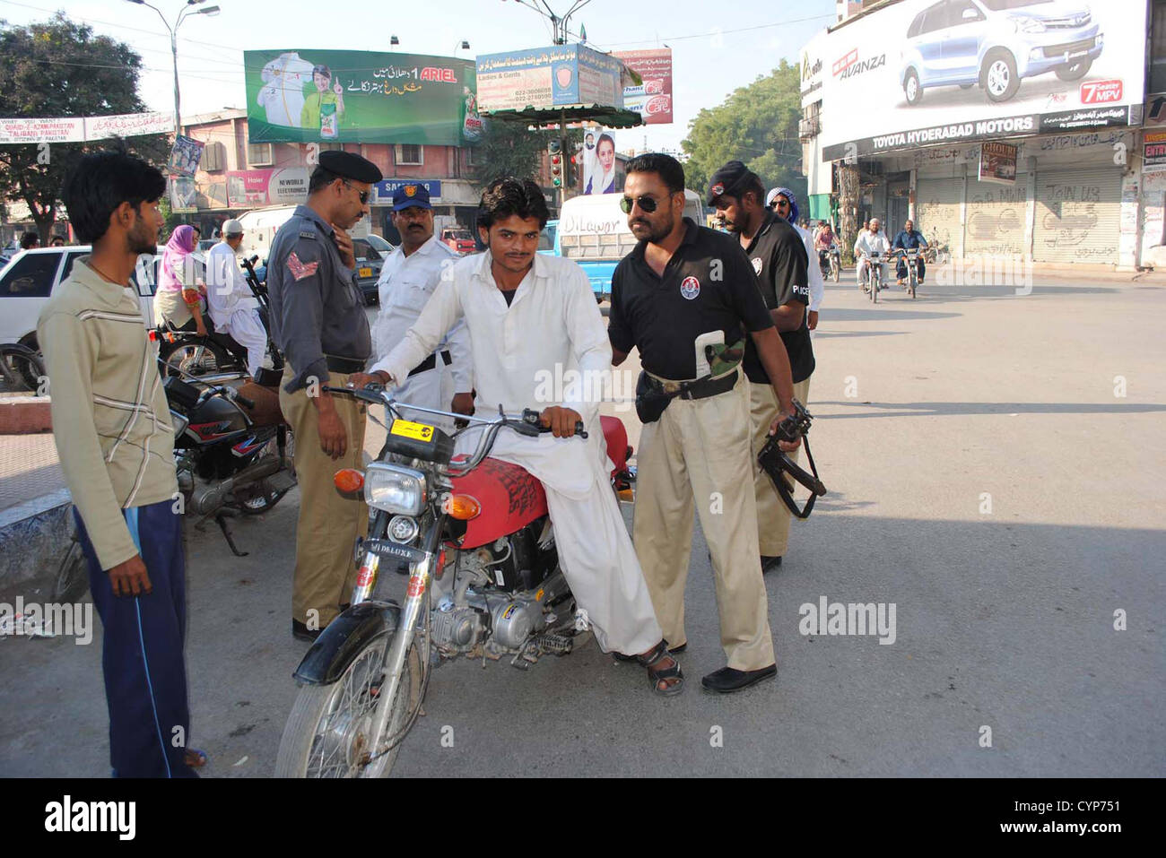 Policemen search a bike rider during snap checking at Pakistan Chowk in ...