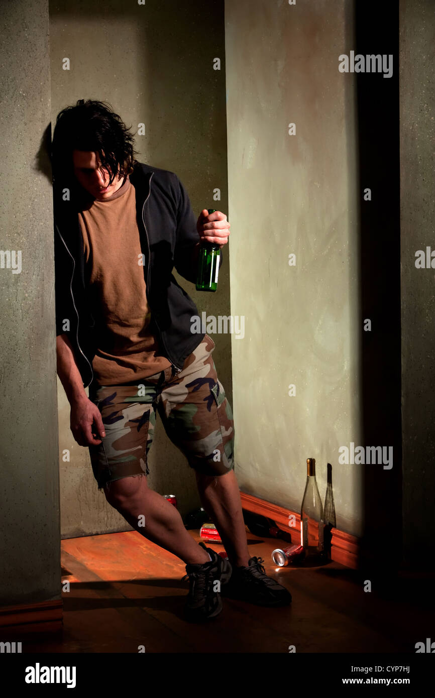 Drunk young man leaning on a wall with beer bottle Stock Photo - Alamy