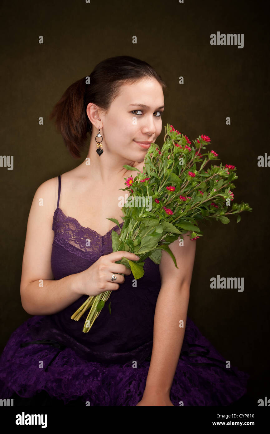 Pretty girl in funky purple outfit on green background with flowers ...