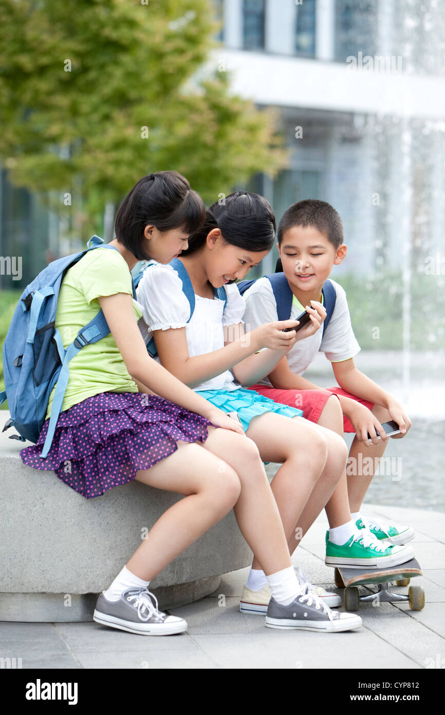 Schoolchildren playing smart phones together Stock Photo - Alamy