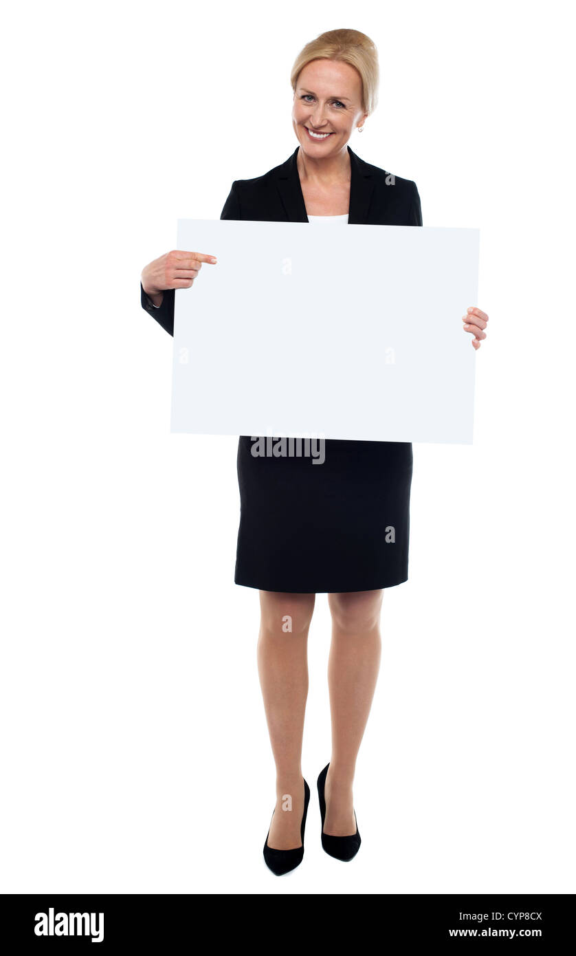 Female executive pointing towards blank white ad board and smiling at ...