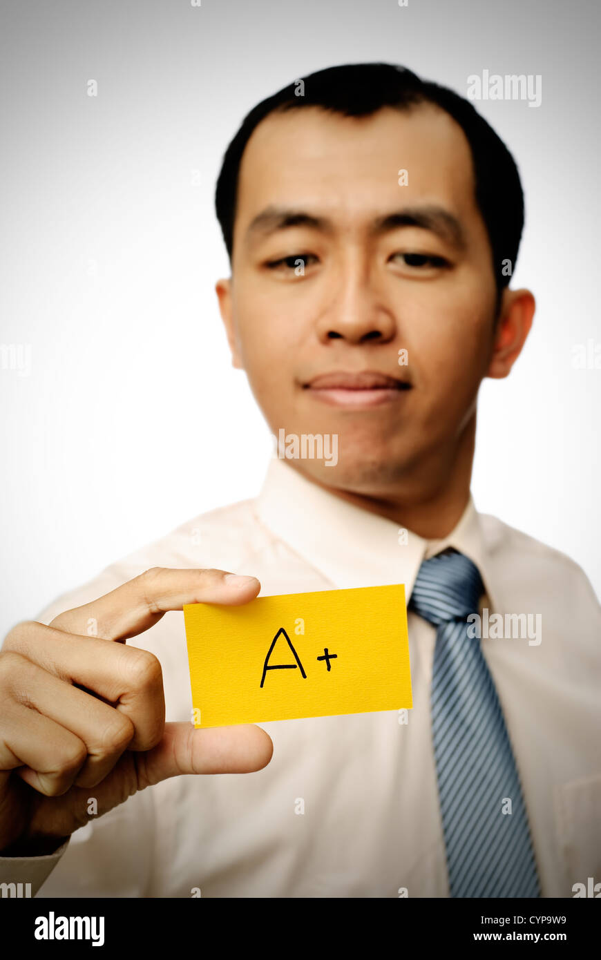 Successful businessman holding A+ card in yellow color Stock Photo - Alamy