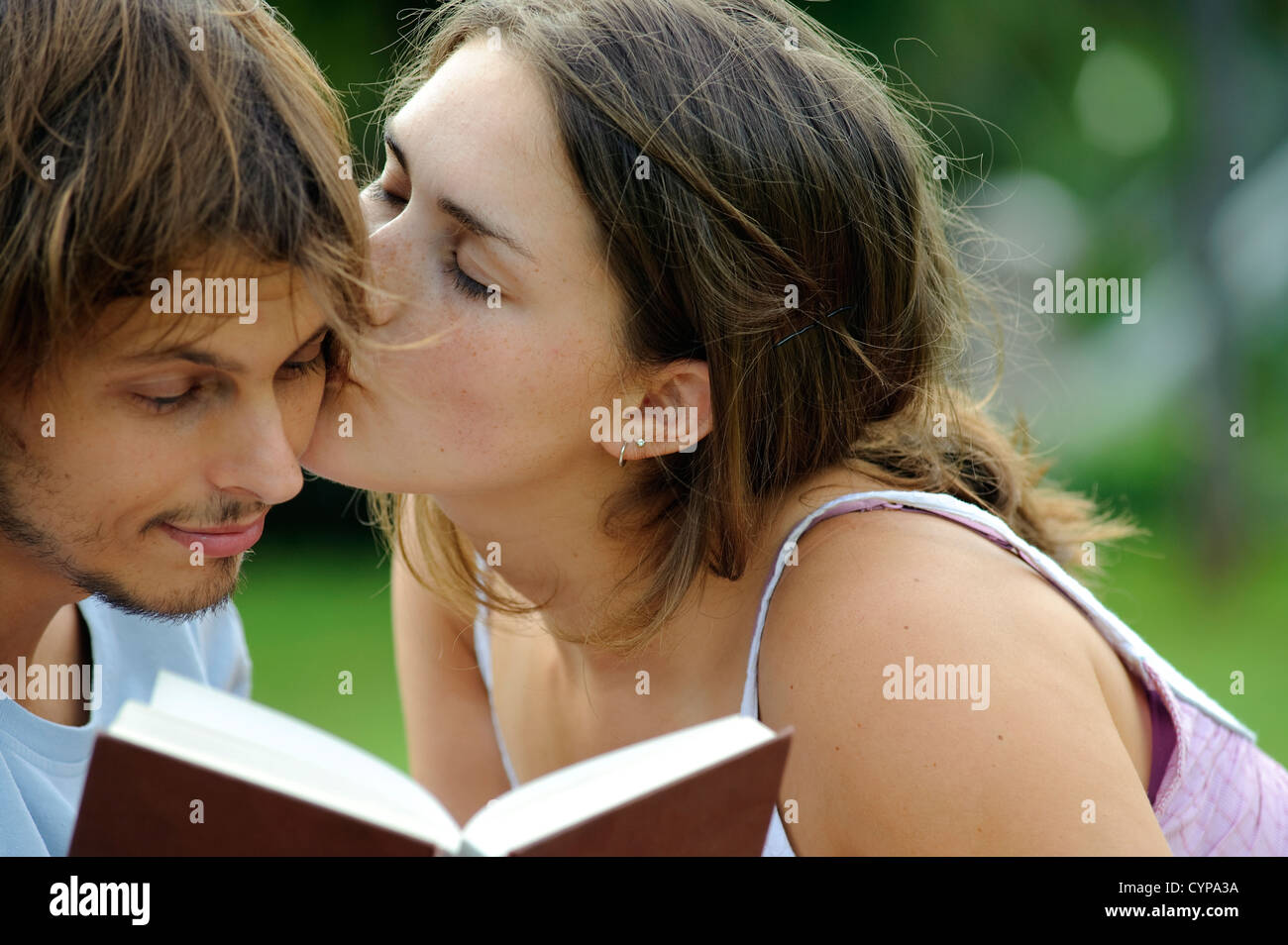 Attractive couple read together in the park Stock Photo - Alamy