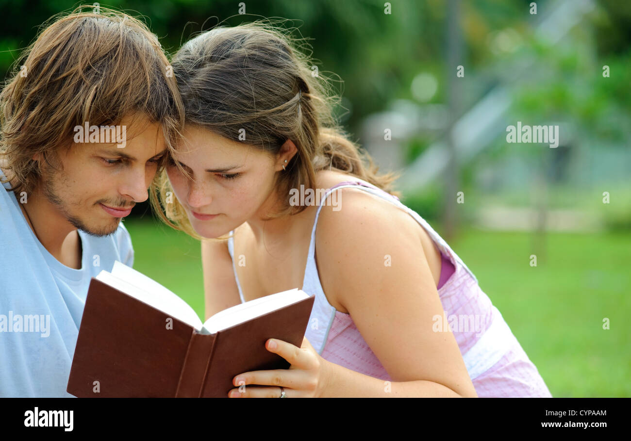 Attractive couple read together in the park Stock Photo - Alamy