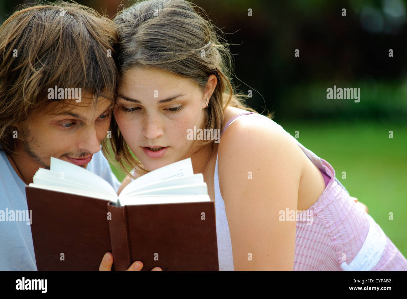 Attractive couple read together in the park Stock Photo - Alamy