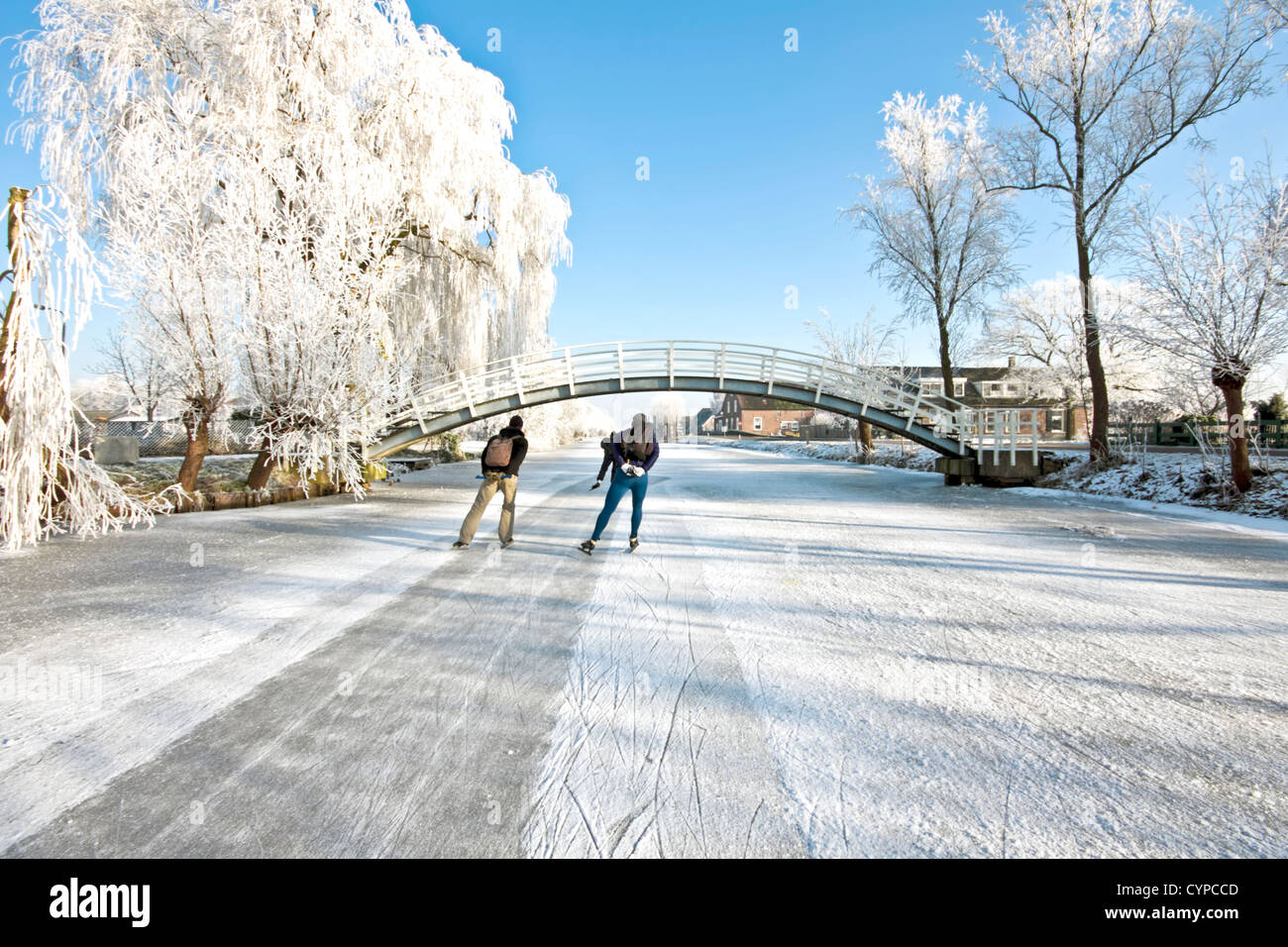 Typically dutch: ice skating on a frozen canal in the countrysidel on a ...