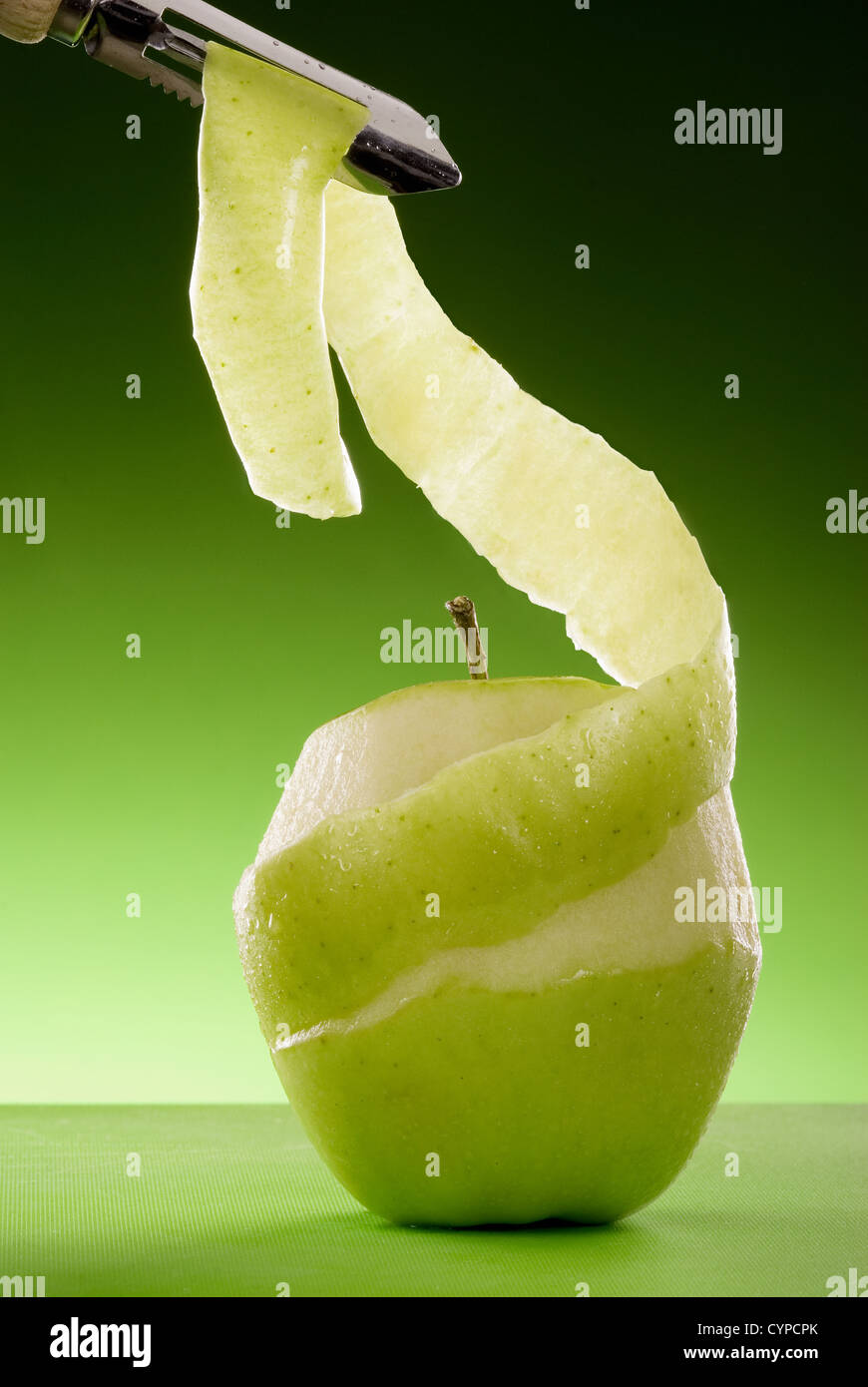 partially peeled green apple on green board isolated on graduated green ...