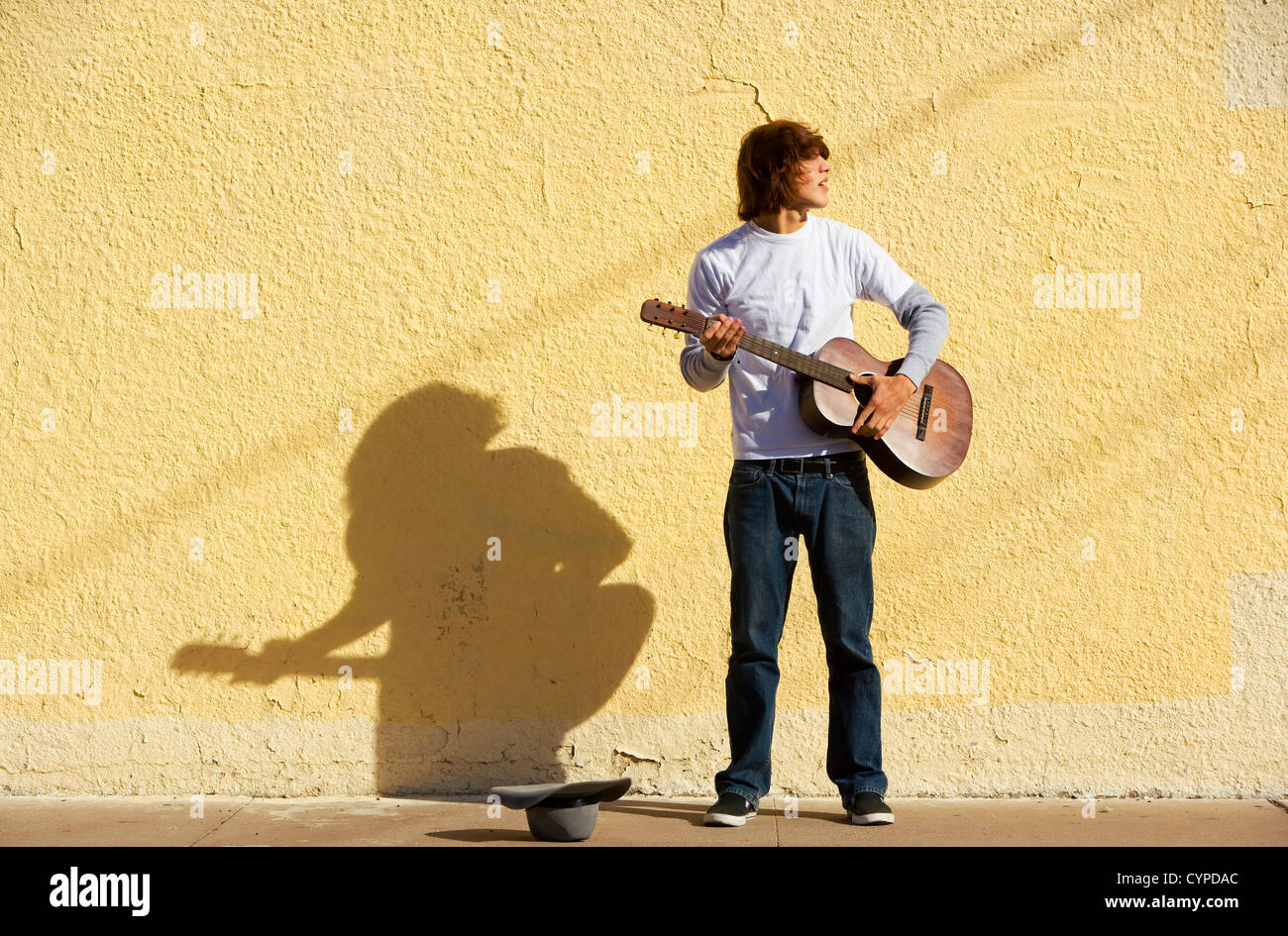 Young male musician alone on the sidewalk with guitar Stock Photo - Alamy