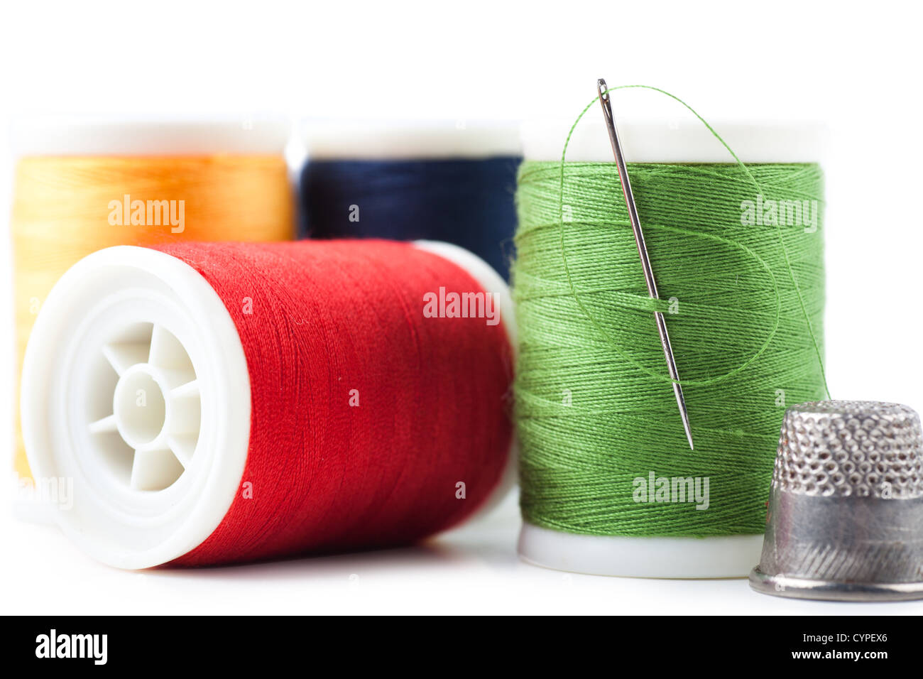 Spools with green, yellow, red and blue threads and needle Stock Photo ...