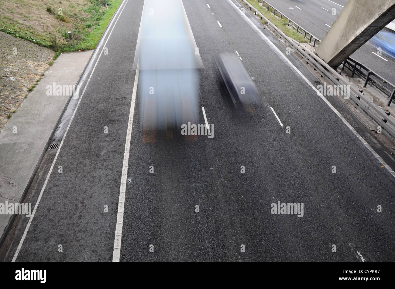 Cars and lorries driving under a motorway bridge in England Stock Photo ...