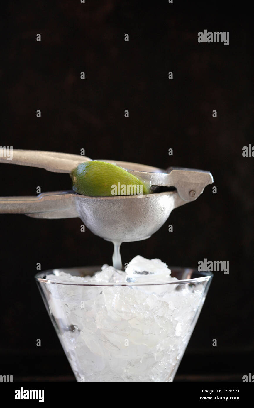 Lime being squeezed over ice Stock Photo - Alamy