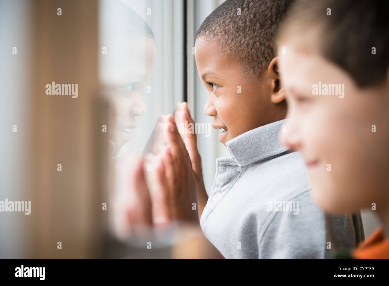 Boys looking out window together Stock Photo - Alamy