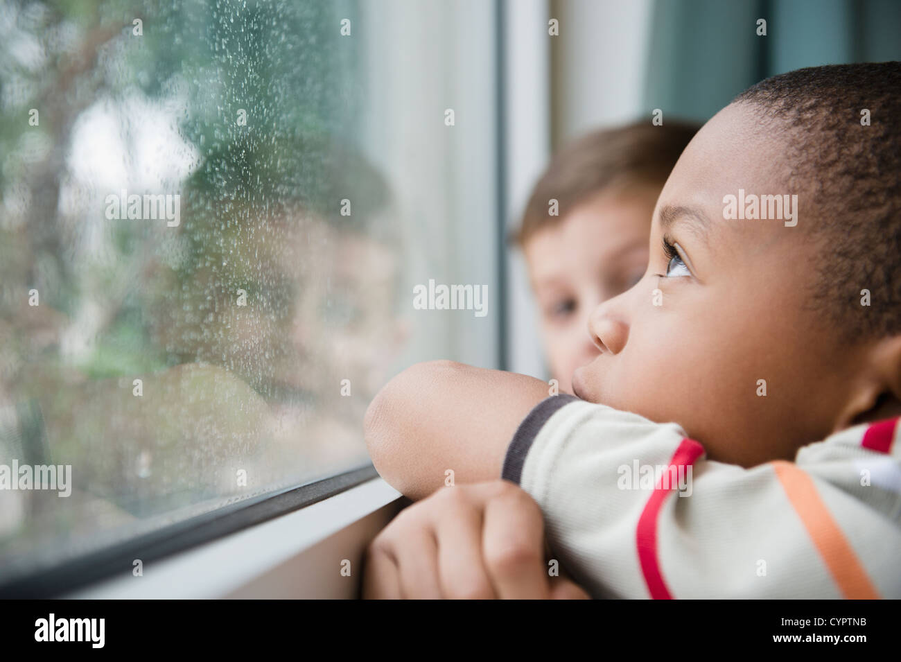 Boys looking out window together Stock Photo - Alamy