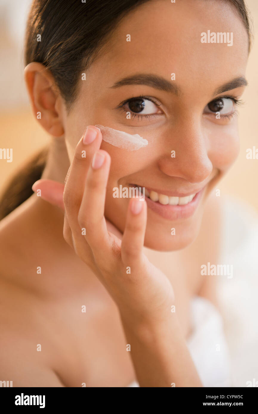 Hispanic teenager putting on face lotion Stock Photo - Alamy