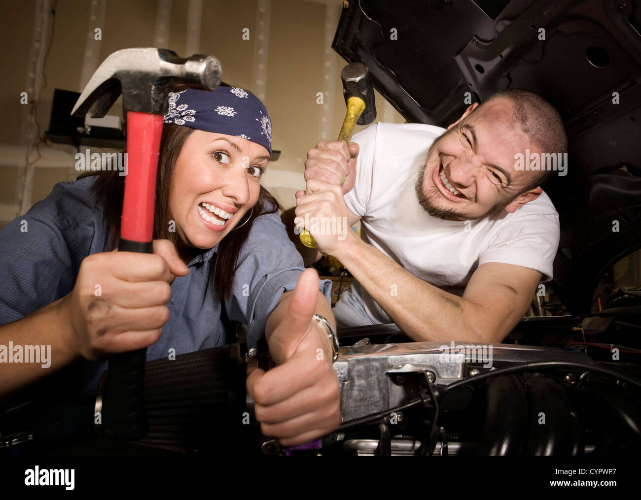 Hapless mechanics working on car engine with hammers Stock Photo - Alamy