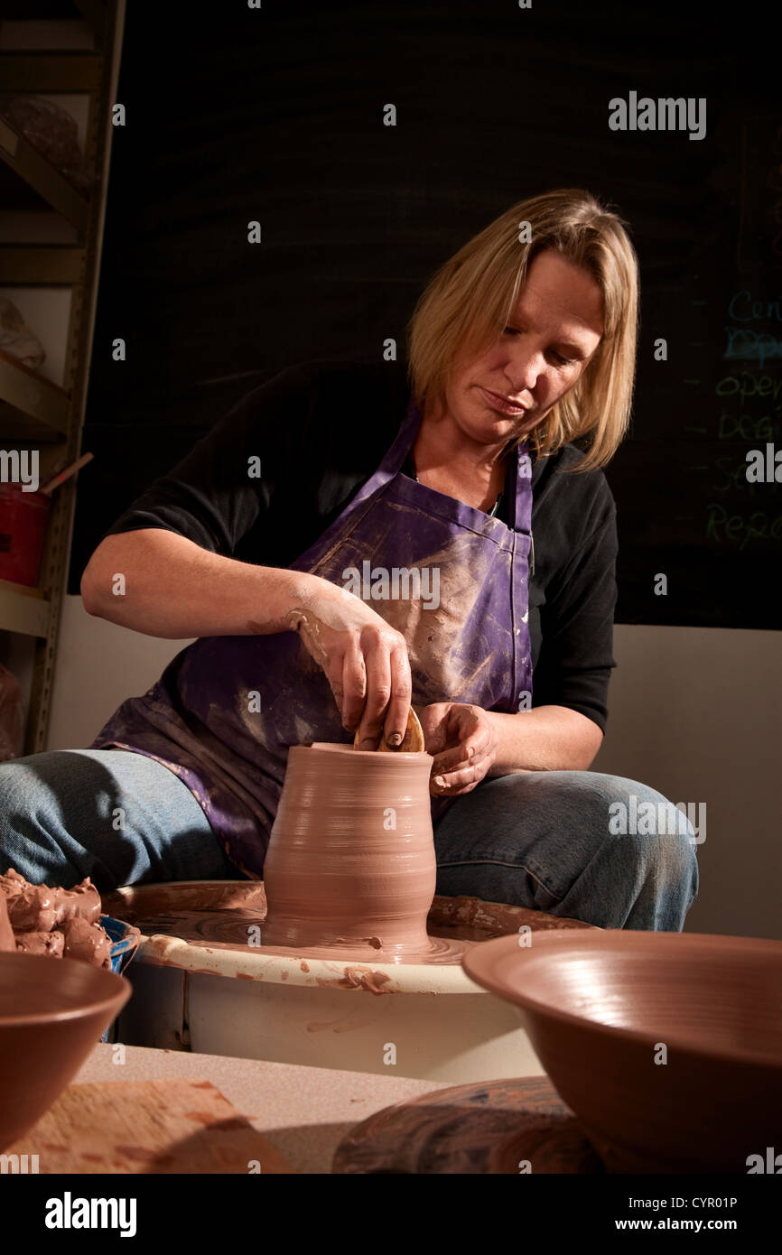 Female potter at wheel shaping clay with wooden jigger Stock Photo - Alamy