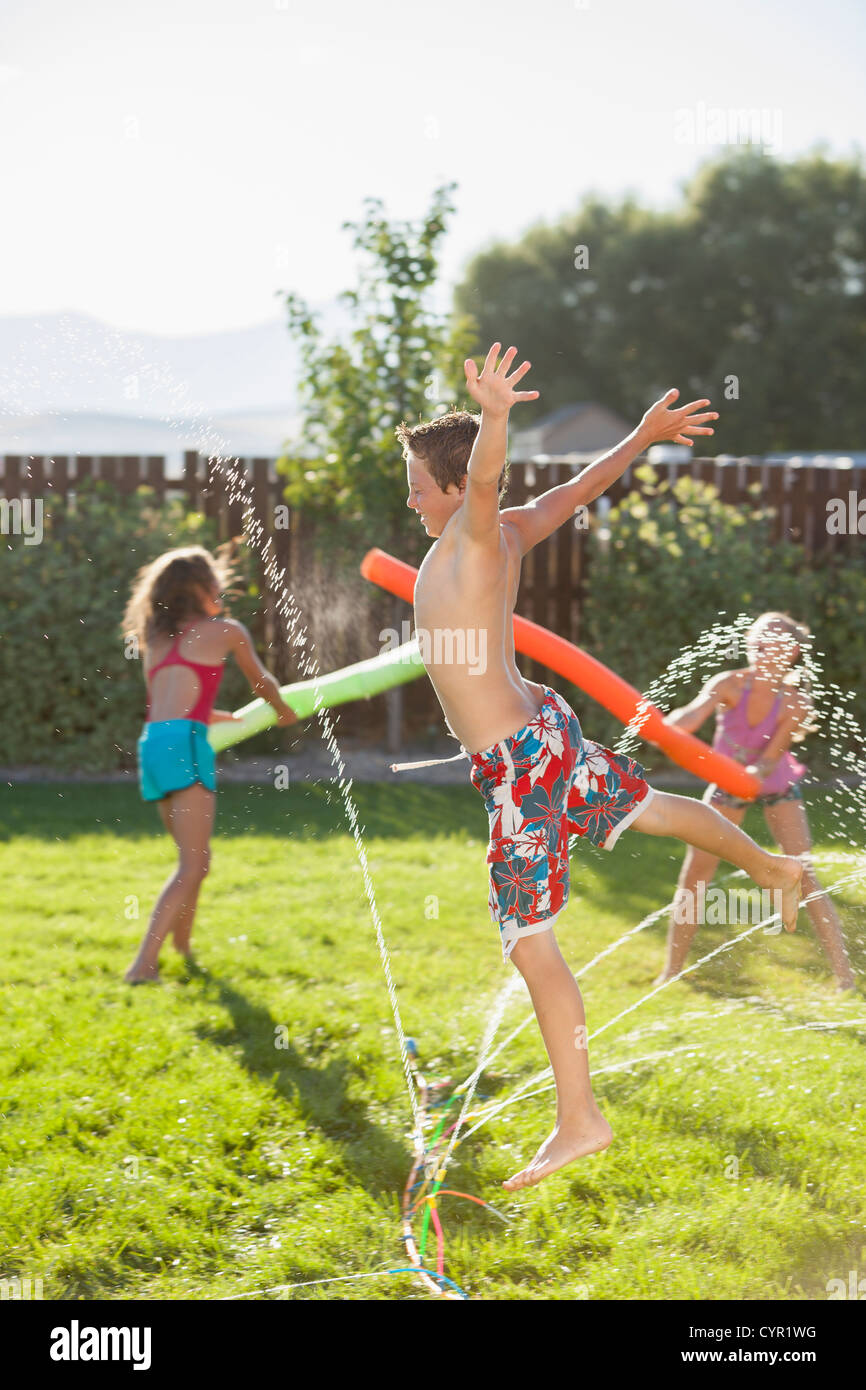 Caucasian children playing in the sprinkler Stock Photo - Alamy