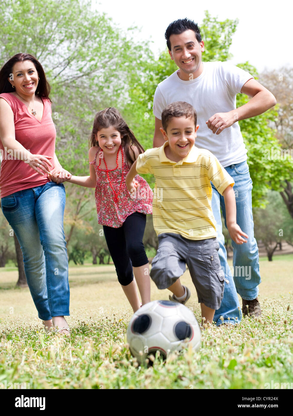 Happy family run to the soccer ball in the park, outdoor Stock Photo ...