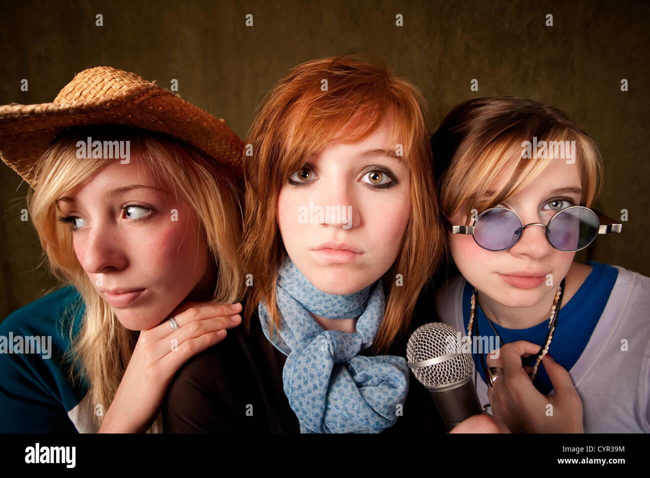 Portrait of three pretty young girls with a microphone on green ...