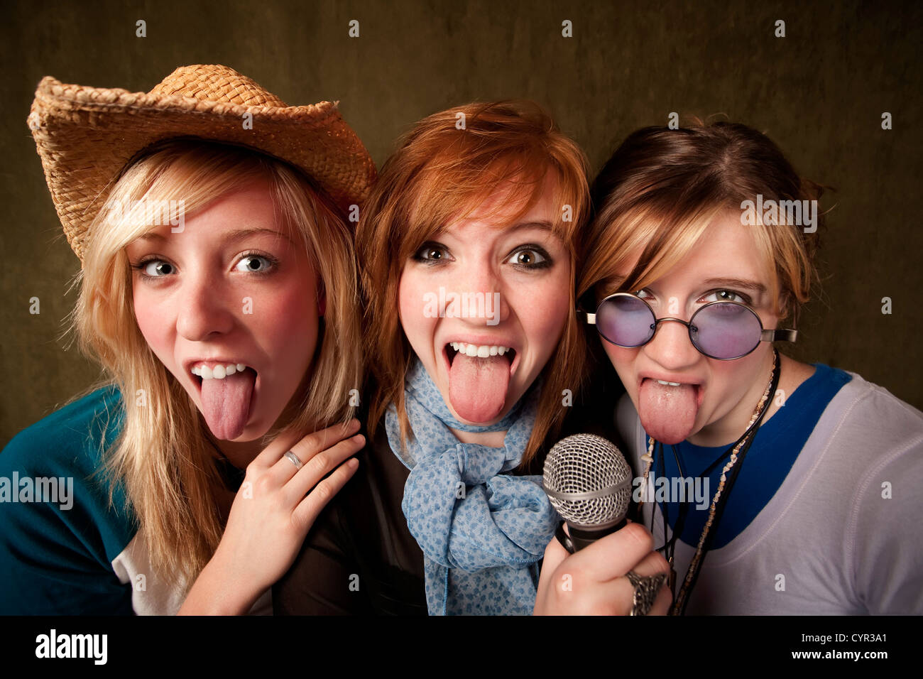 Portrait of three pretty young girls and tongues out with a microphone ...