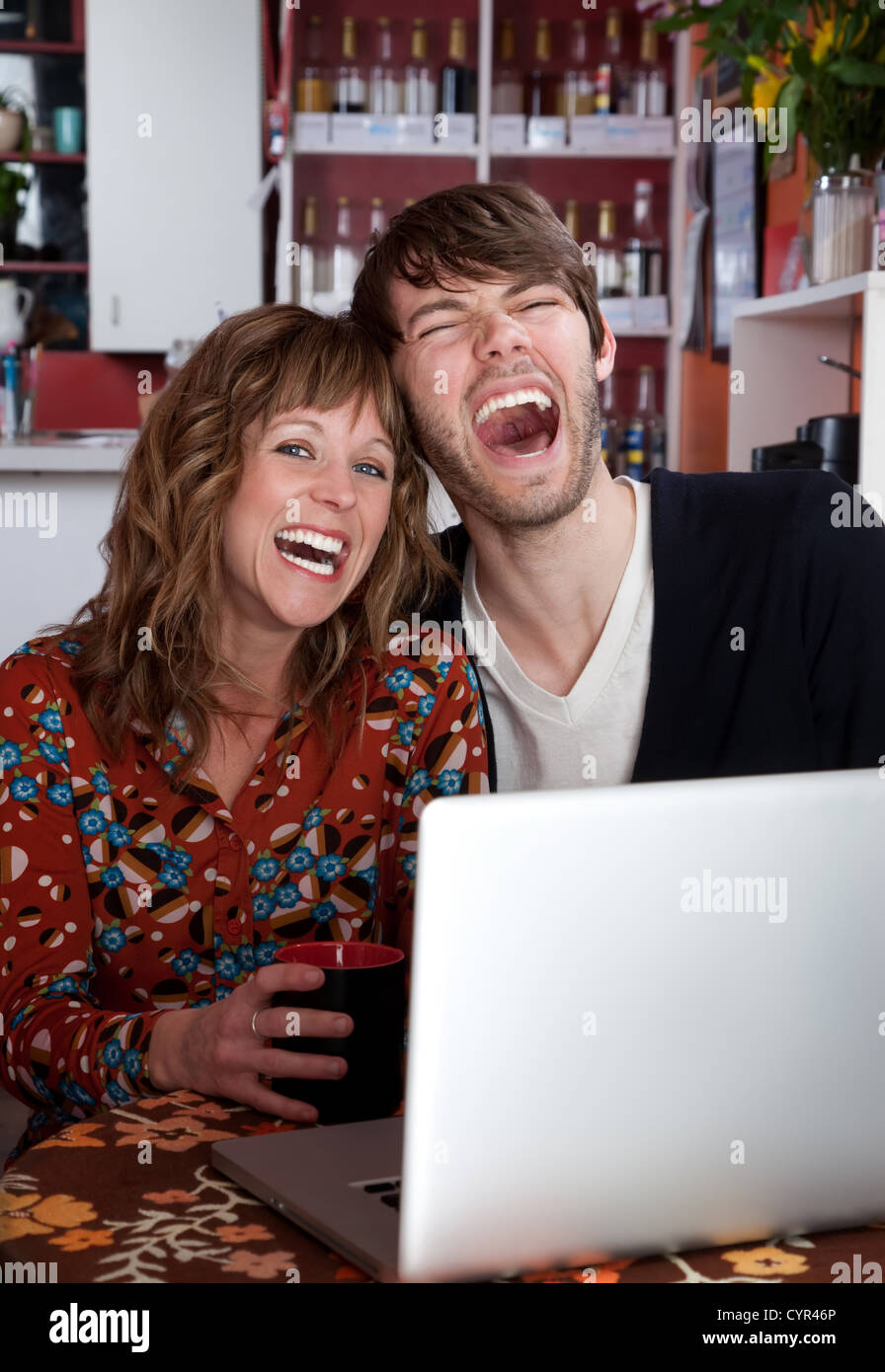 Laughing couple using a computer at a coffee house Stock Photo - Alamy