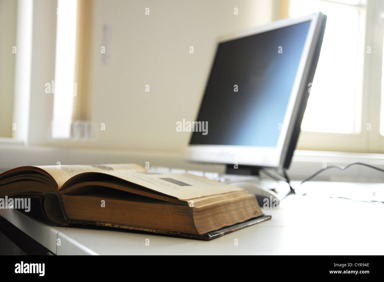 old books and computer on a desk in a library Stock Photo - Alamy