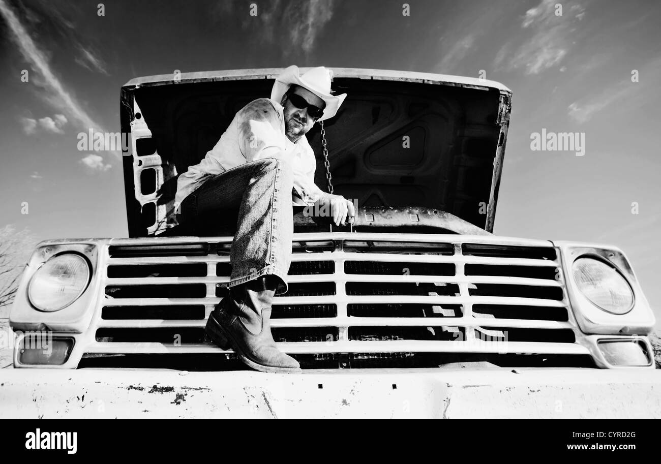 Man in cowboy hat under the hood of truck Stock Photo - Alamy