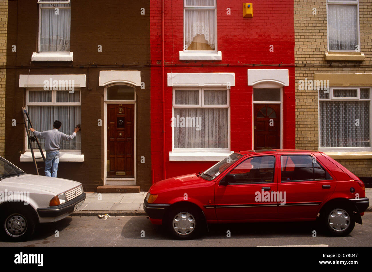 A window cleaner leathers down a freshly washed window of a terraced ...