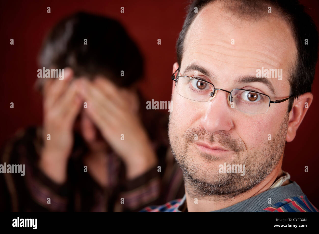 Guilty man with upset woman in the background Stock Photo - Alamy