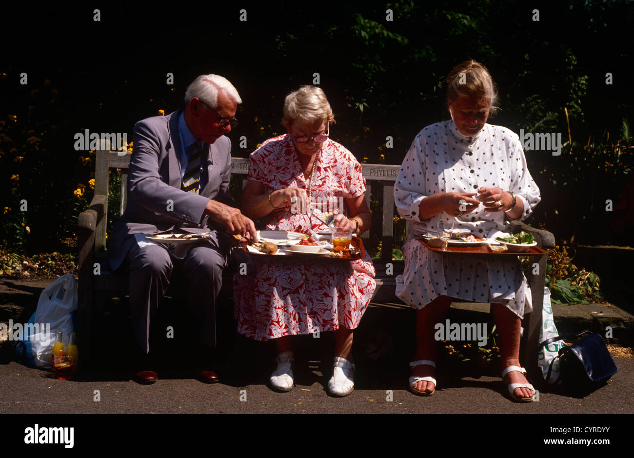 Elderly friends eat lunch on their laps during a mid-day rest at the ...