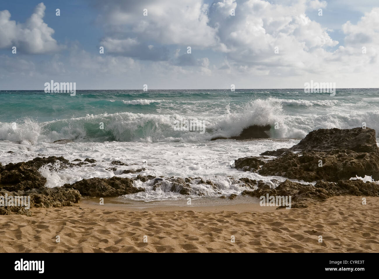 Beach with sand and rock and sea water wave under dramatic blue sky ...