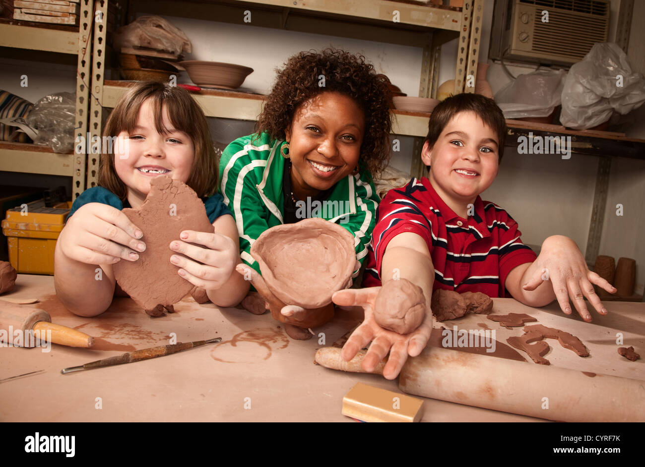 Teacher and young students having fun ion clay studio Stock Photo - Alamy