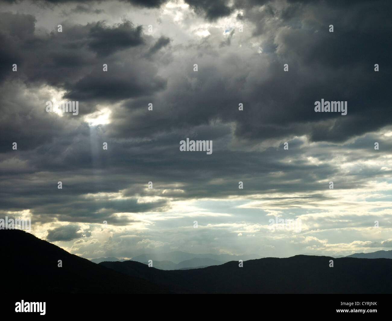 A hole in a stormy cloud let a ray of light pass through Stock Photo ...