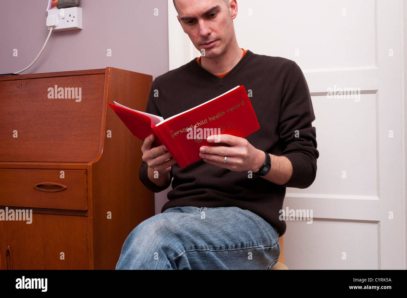 Father looking at his child's Child Health Record book Stock Photo - Alamy