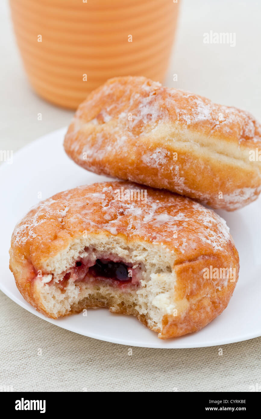 Jam donut with bite taken out and a cup in the background Stock Photo ...