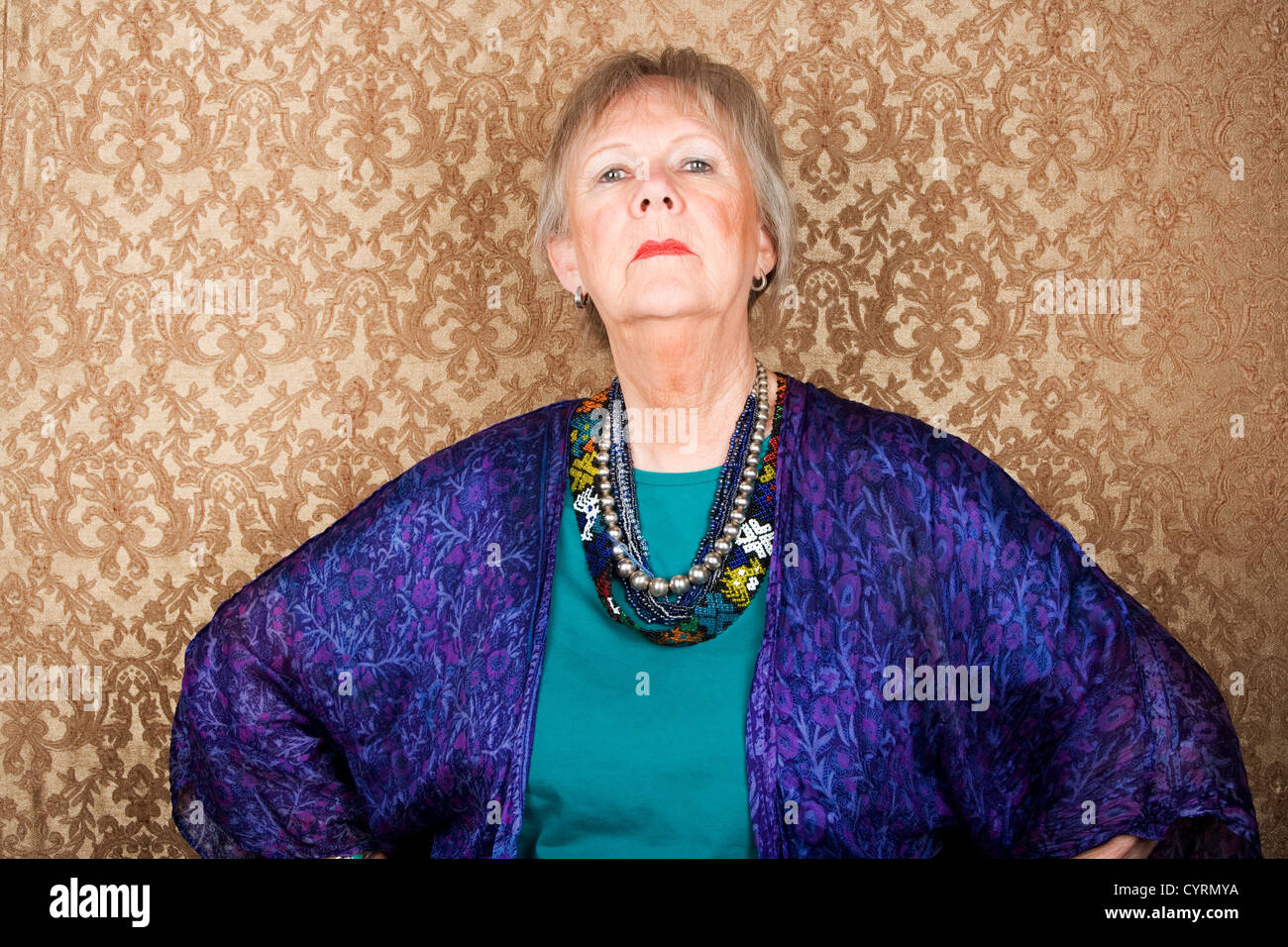Portrait of snooty senior woman in front of gold background Stock Photo ...