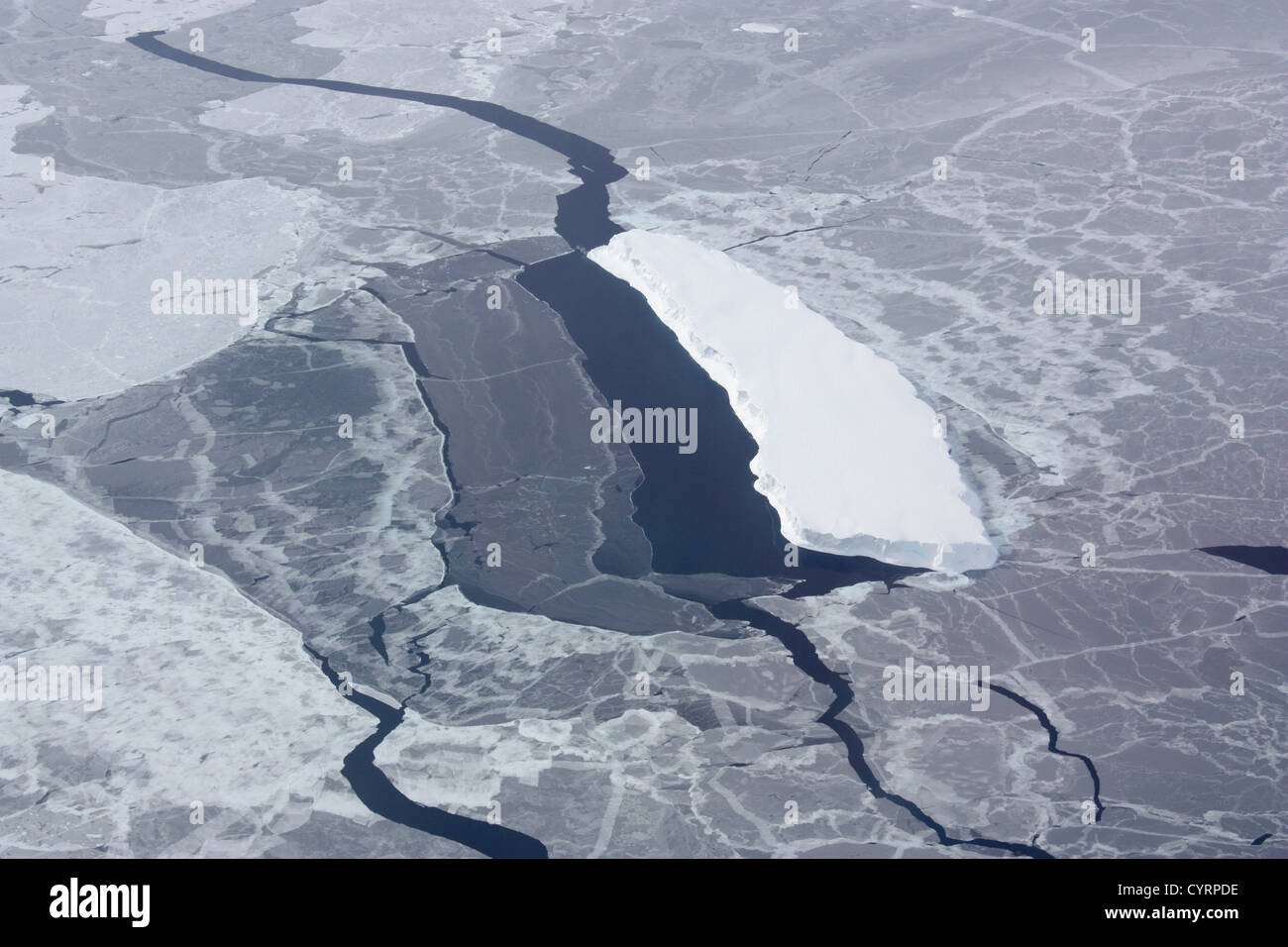 Aerial view of an iceberg embedded in sea ice with a lead on one side ...