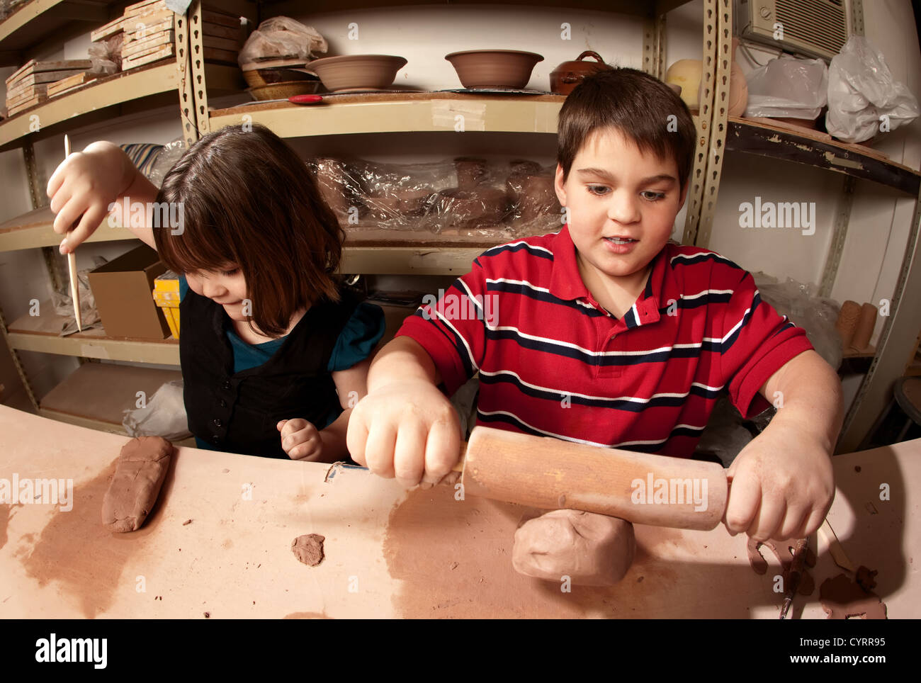 Two cute kids working with clay and playing around in a clay stufio ...