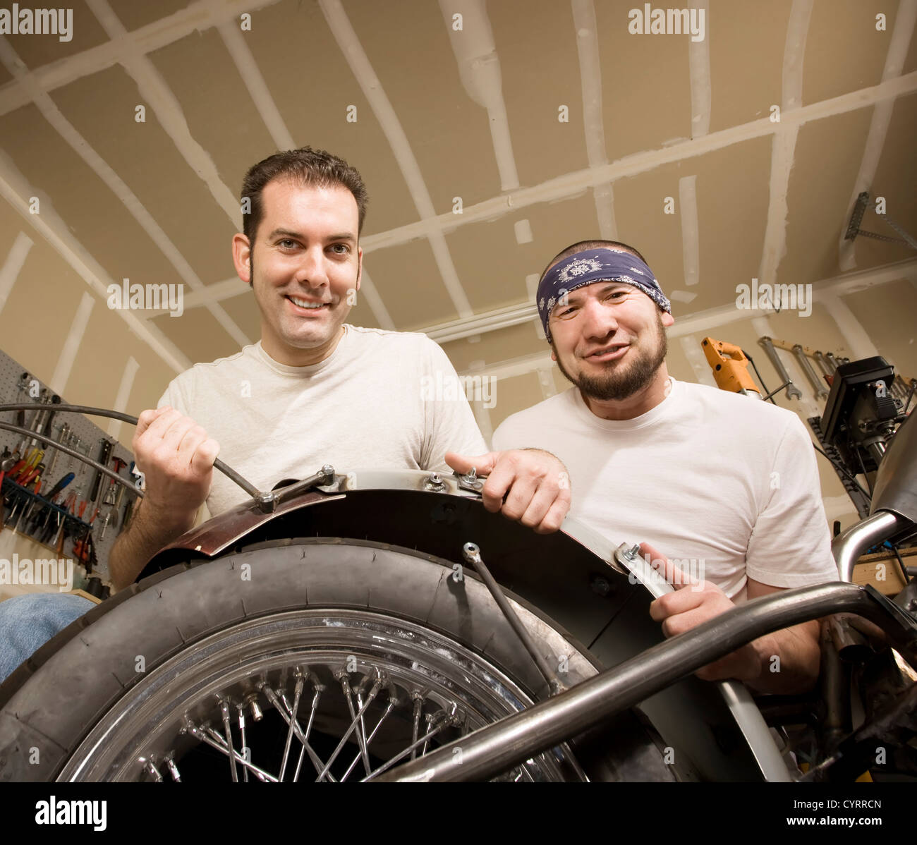 Two men working on a chopper-style motorcycle Stock Photo - Alamy