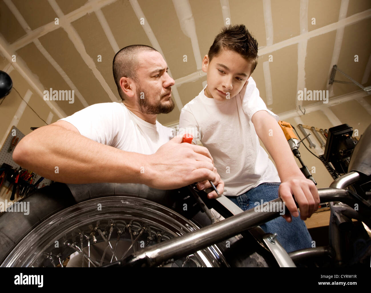 Hispanic father and son working on motorcycle in garage Stock Photo - Alamy
