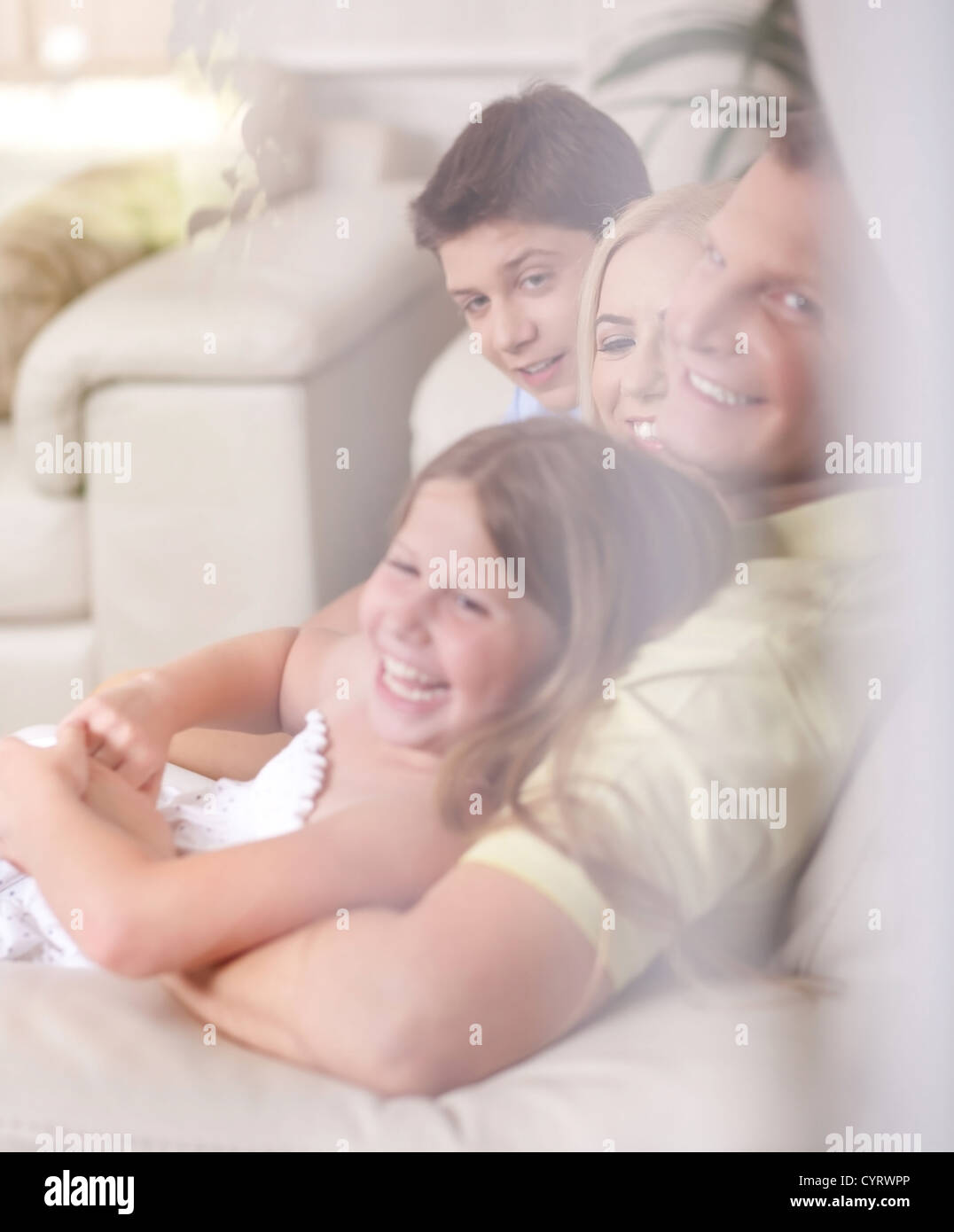 Happy family smiling and looking behind the window glass in living room ...