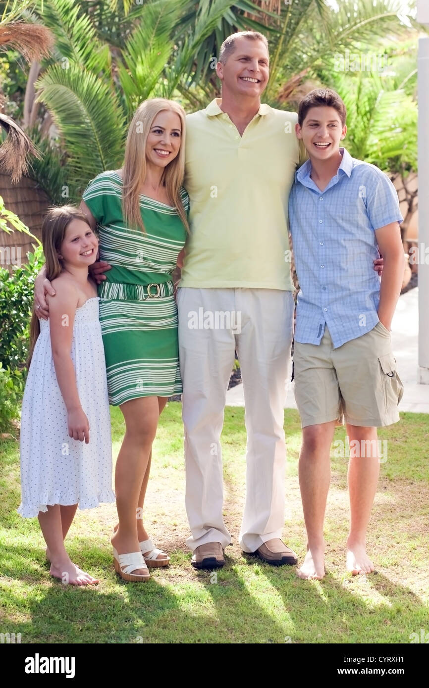 Family in their backyard at home standing and smiling looking at you ...
