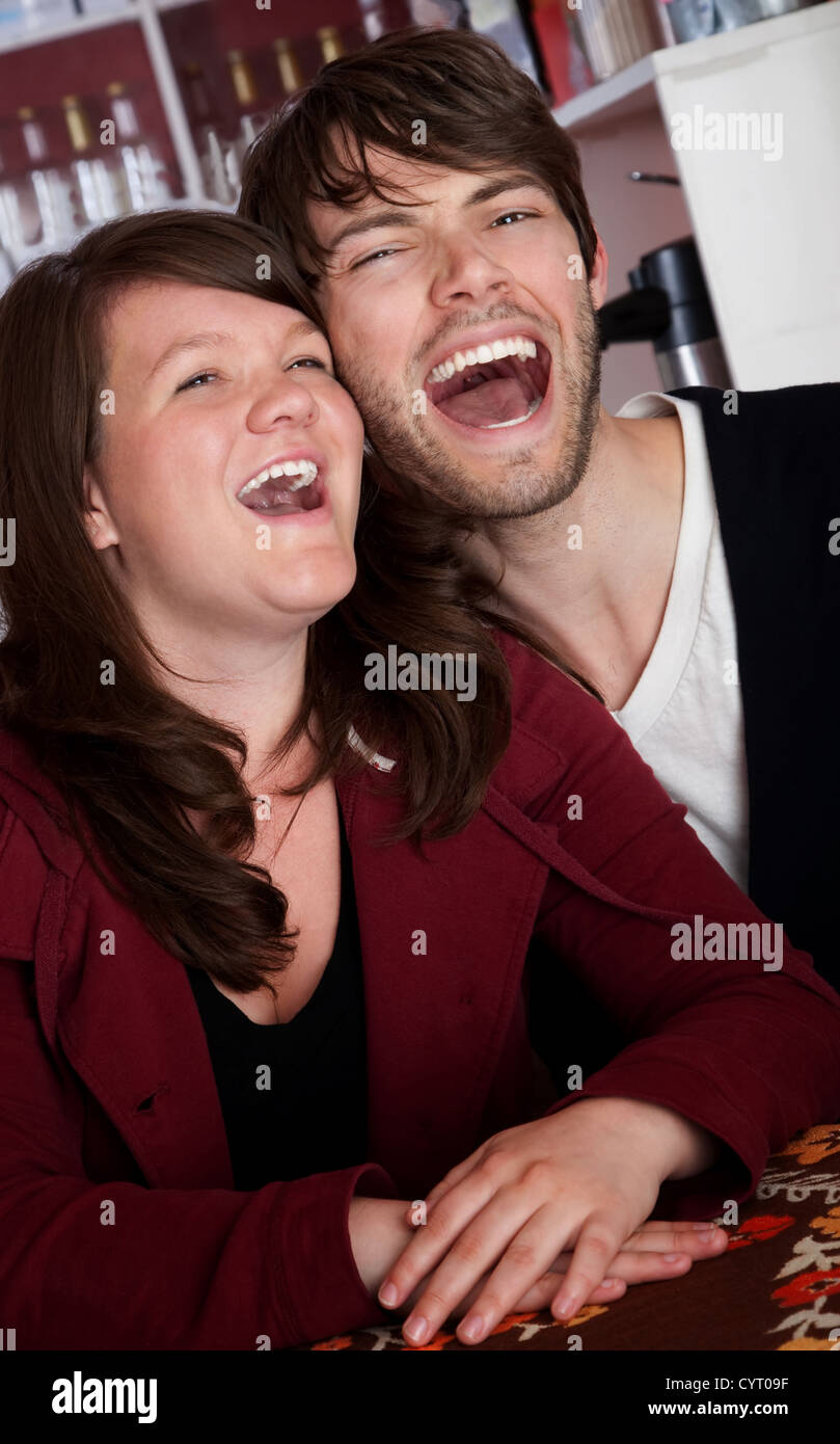 Couple laughing loudly together at a cafe Stock Photo - Alamy