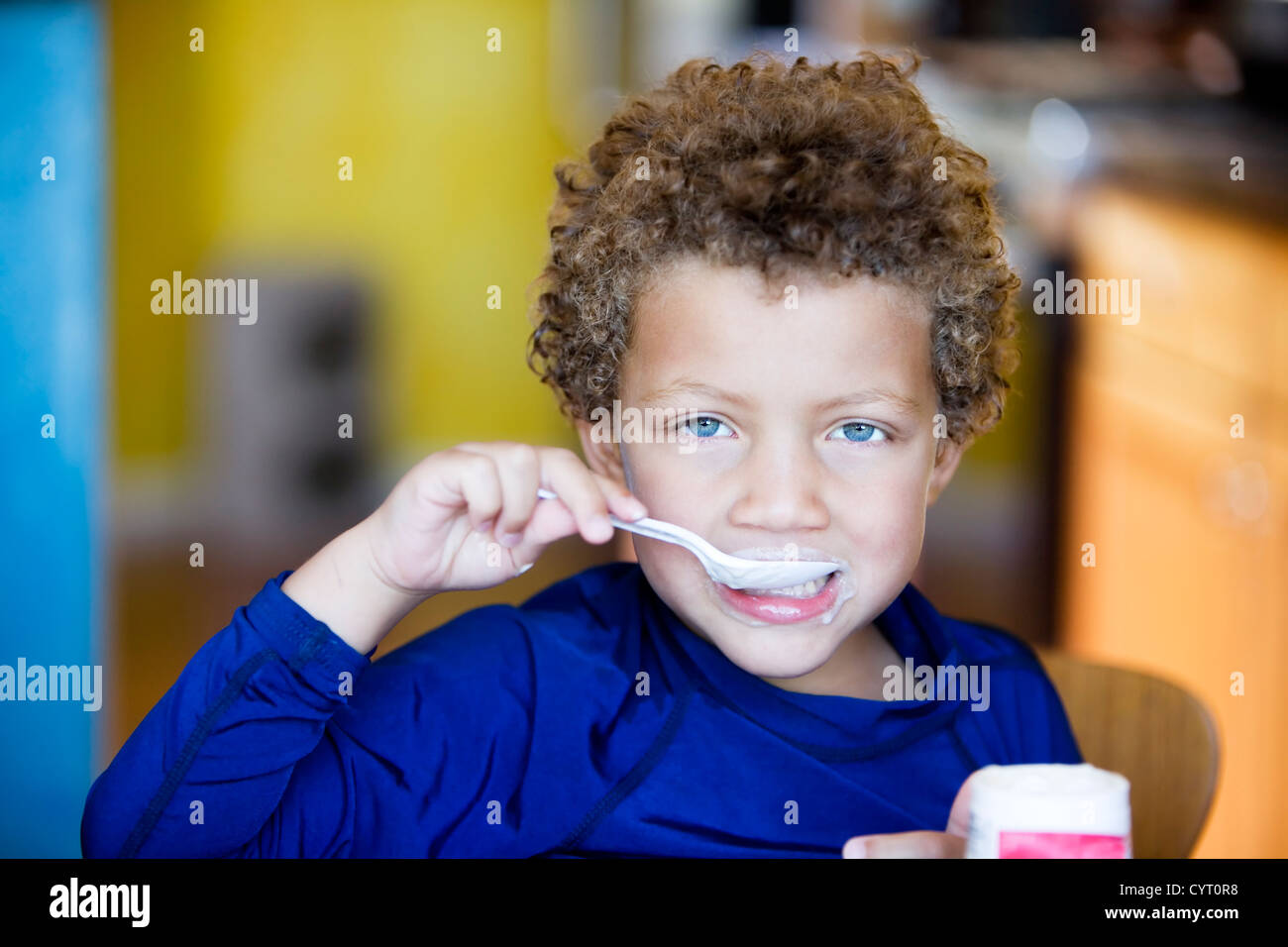 Handsome young boy with blue eyes eating yogurt Stock Photo - Alamy