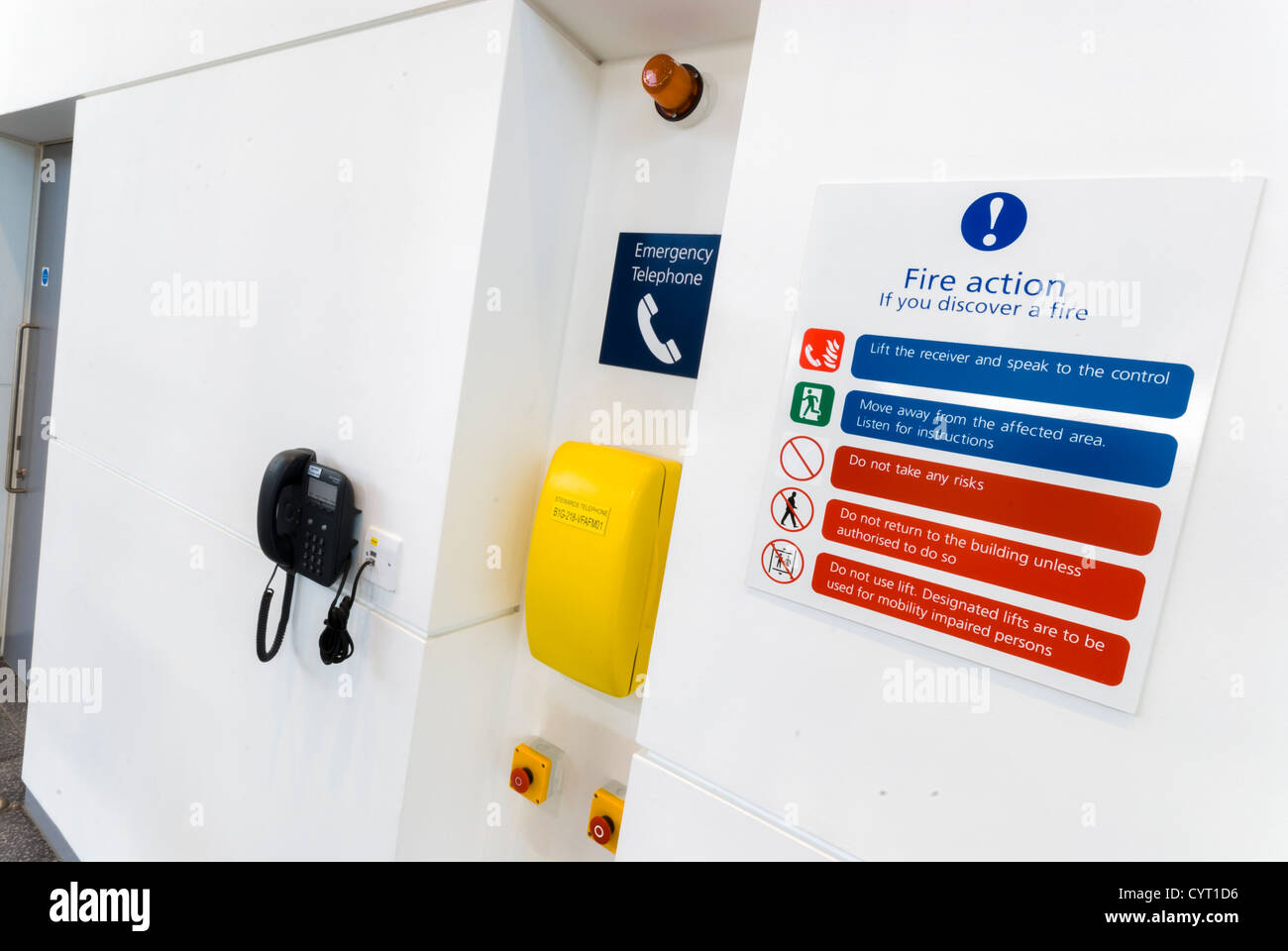 yellow emergency telephone on wall with "what to do in a fire" sign ...