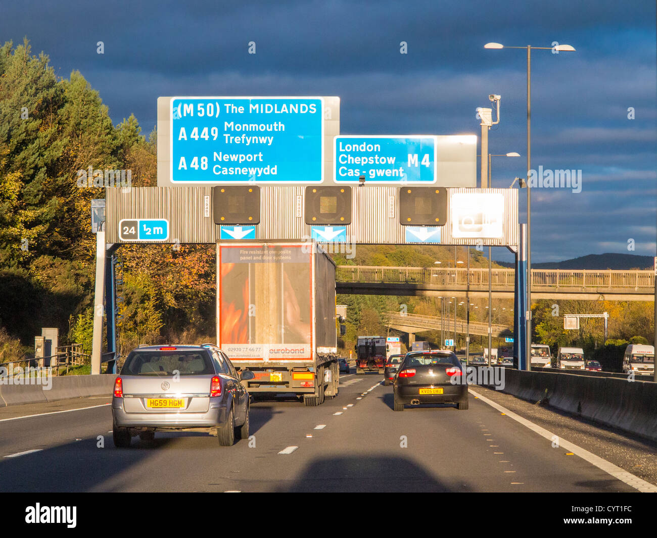 M4 motorway with cars and lorries in Wales with overhead gantry showing ...